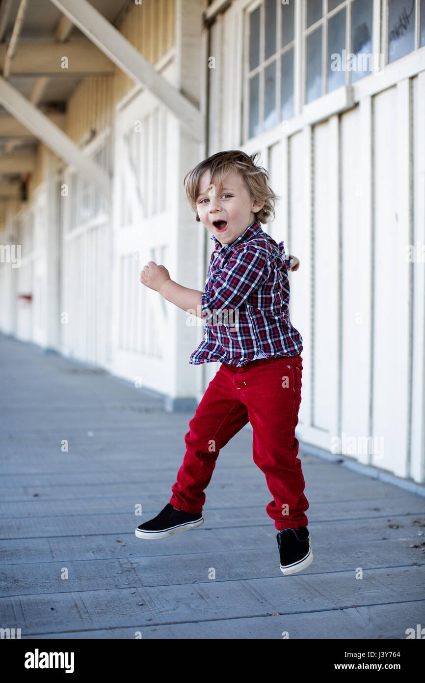 Portrait of cute boy jumping mid air on porch Stock Photo - Alamy