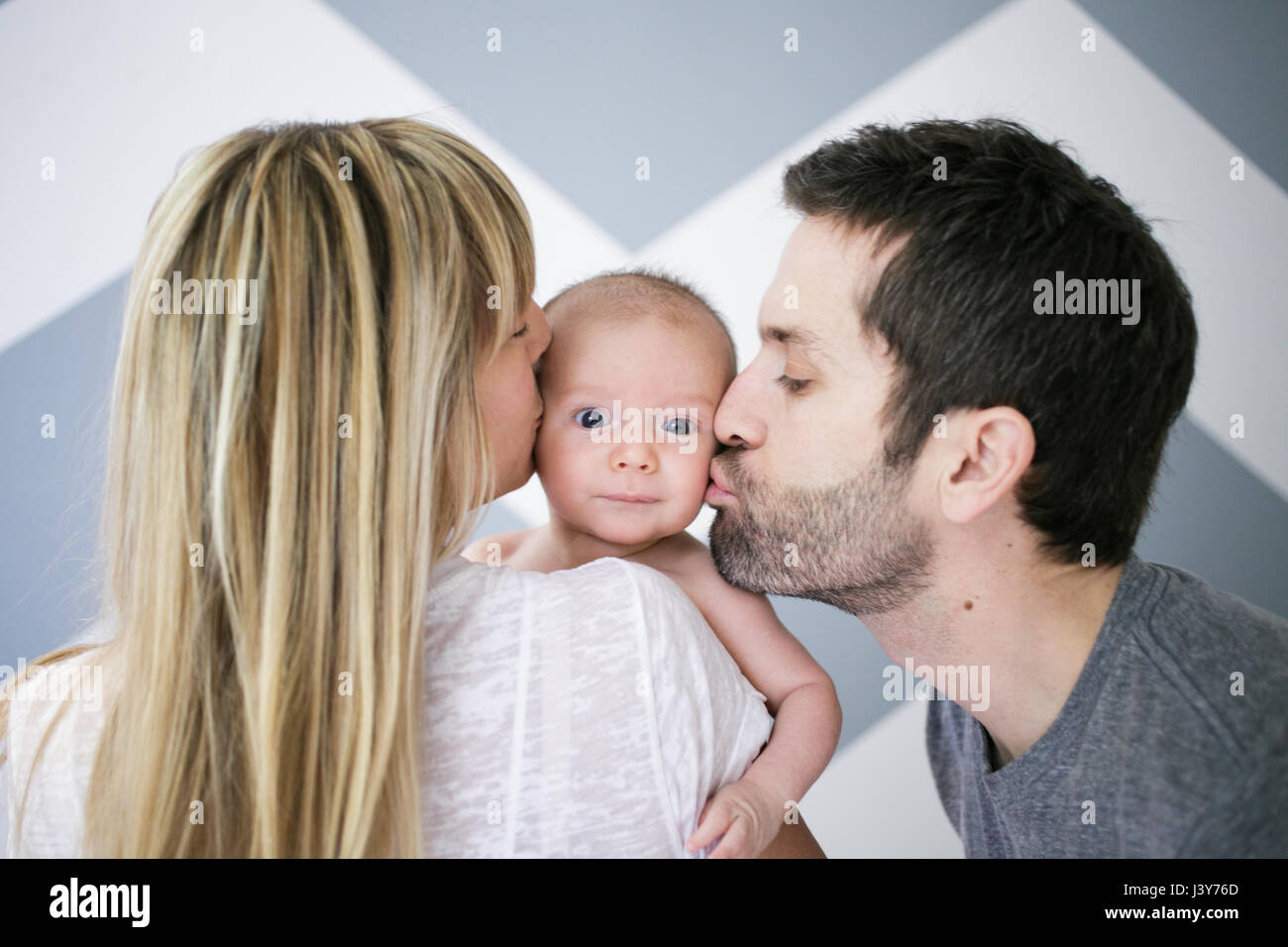 Over shoulder view of mid adult couple kissing baby son on cheek Stock ...