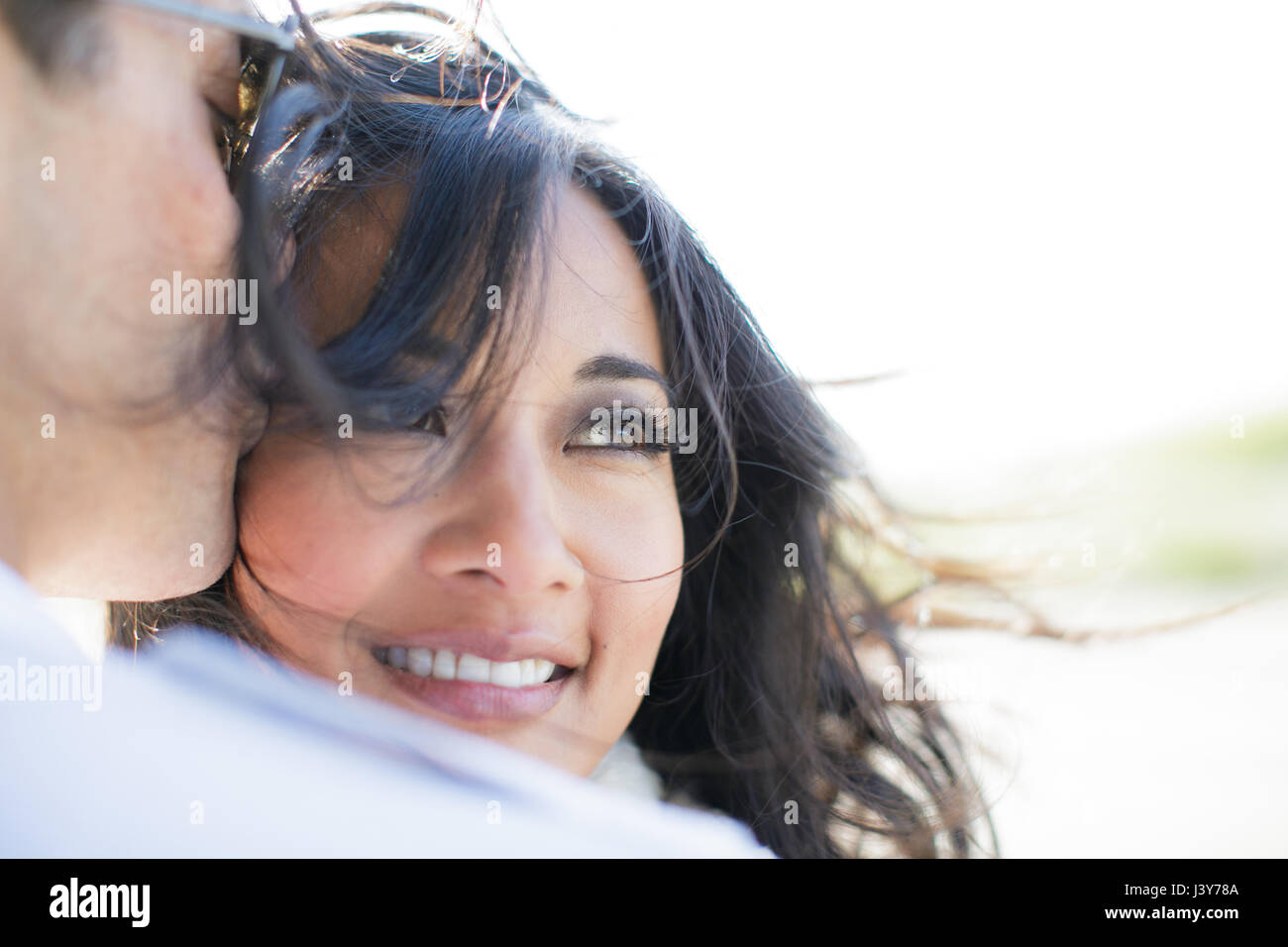 Over shoulder view of man kissing girlfriend on cheek Stock Photo - Alamy