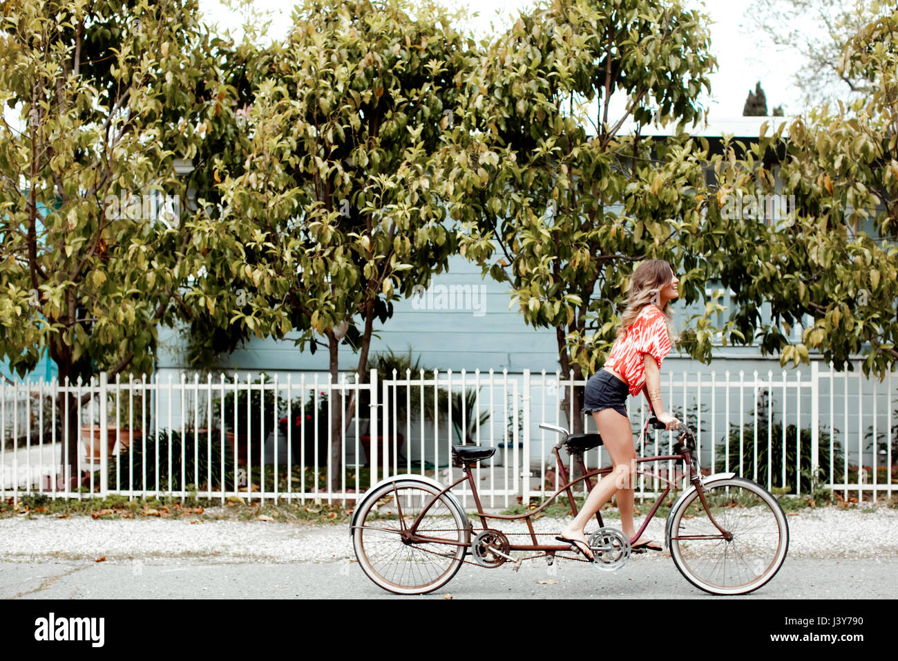 Young woman cycling alone on tandem bicycle along street Stock Photo ...
