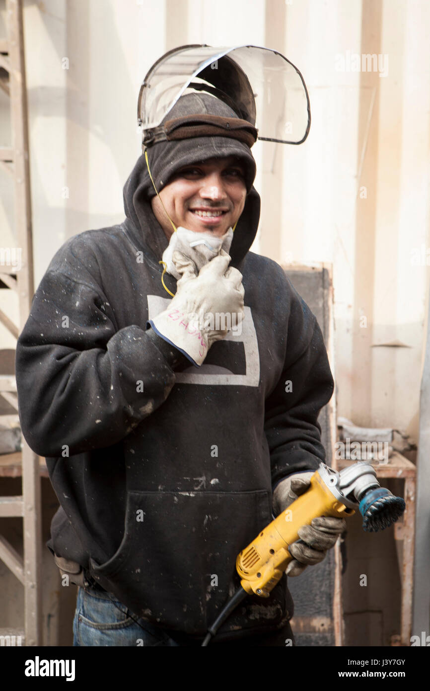 Welder wearing safety equipment holding power tool smiling Stock Photo ...