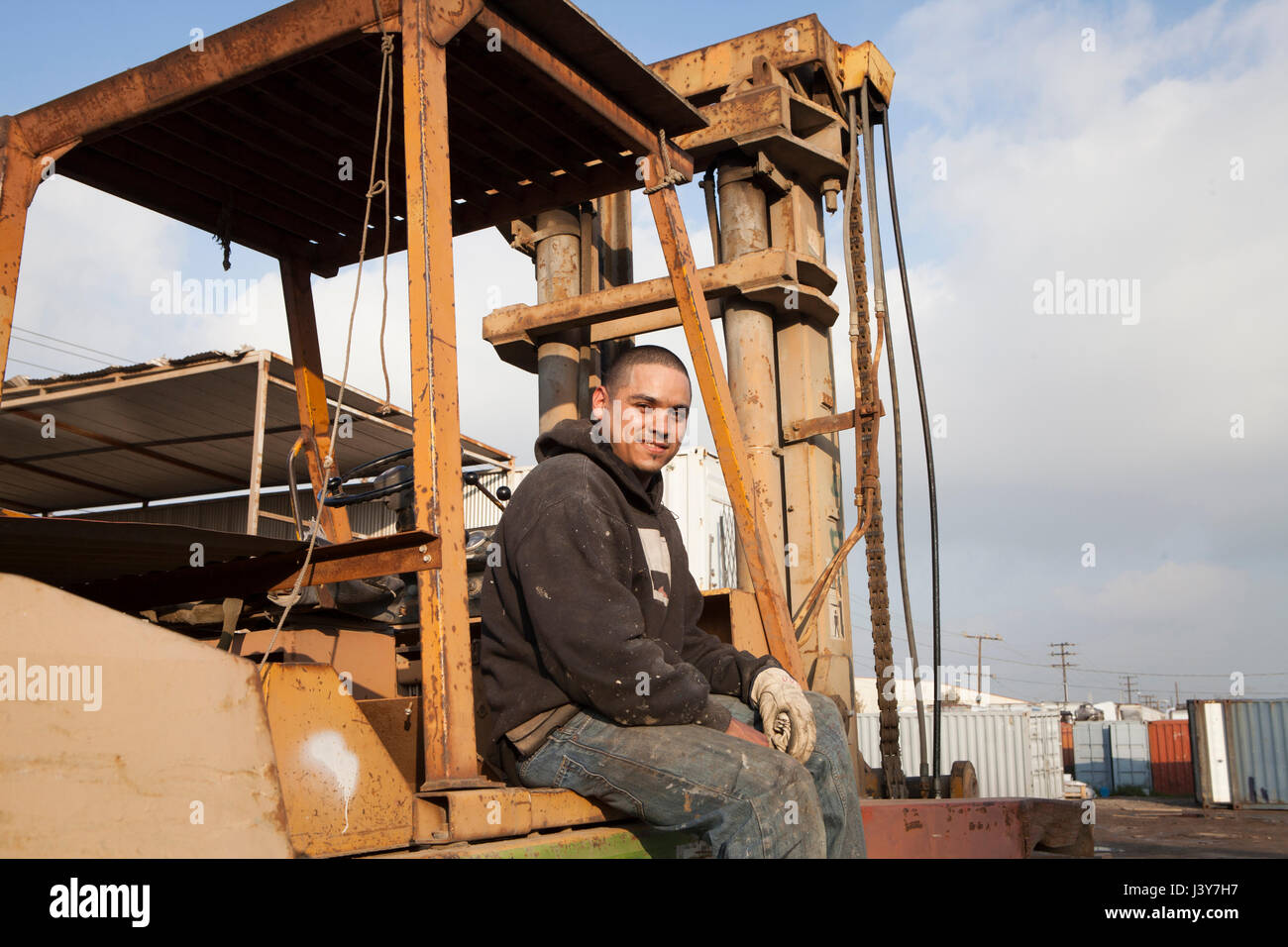 Man on construction site sitting on heavy machinery Stock Photo - Alamy