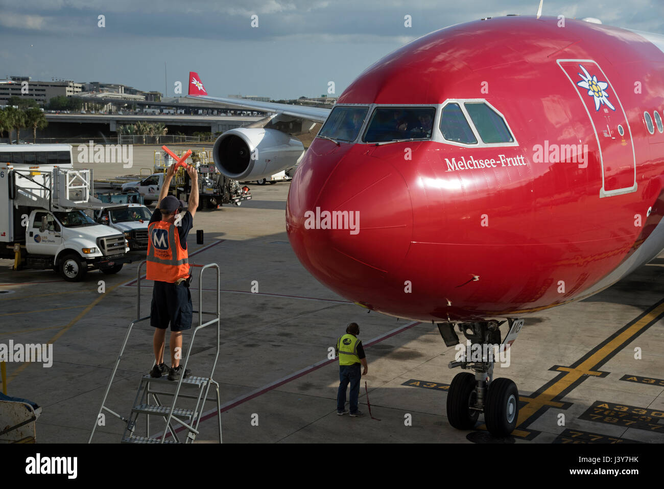 Aircraft marshal using signaling sticks to guide a large passenger jet ...