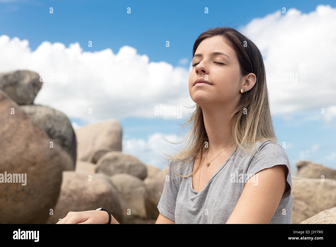Teenage girl sitting on rocks, eyes closed, relaxing Stock Photo - Alamy