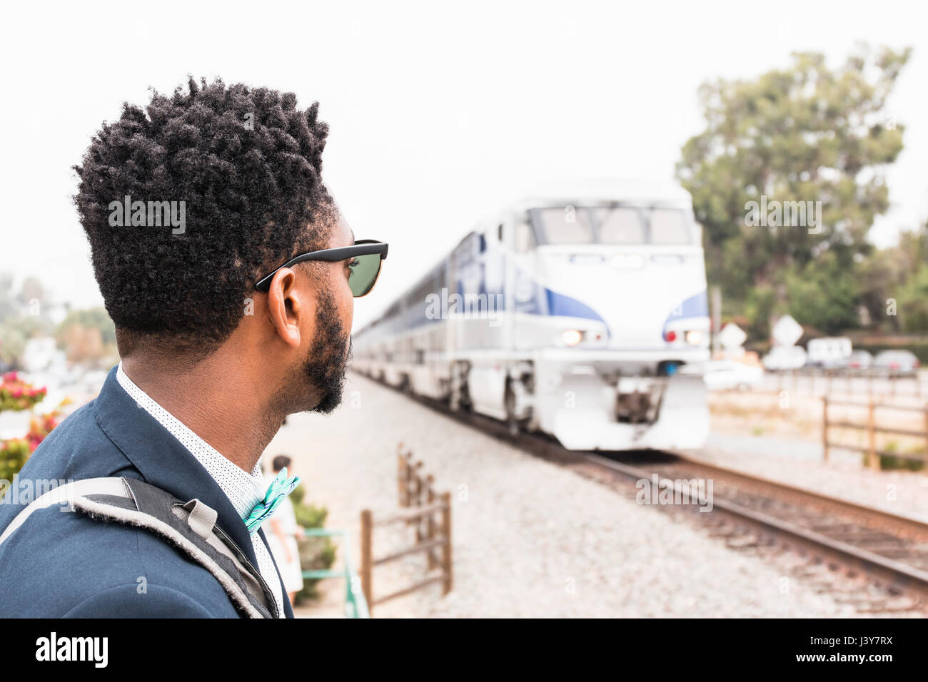 Young businessman watching train arrive at platform Stock Photo - Alamy