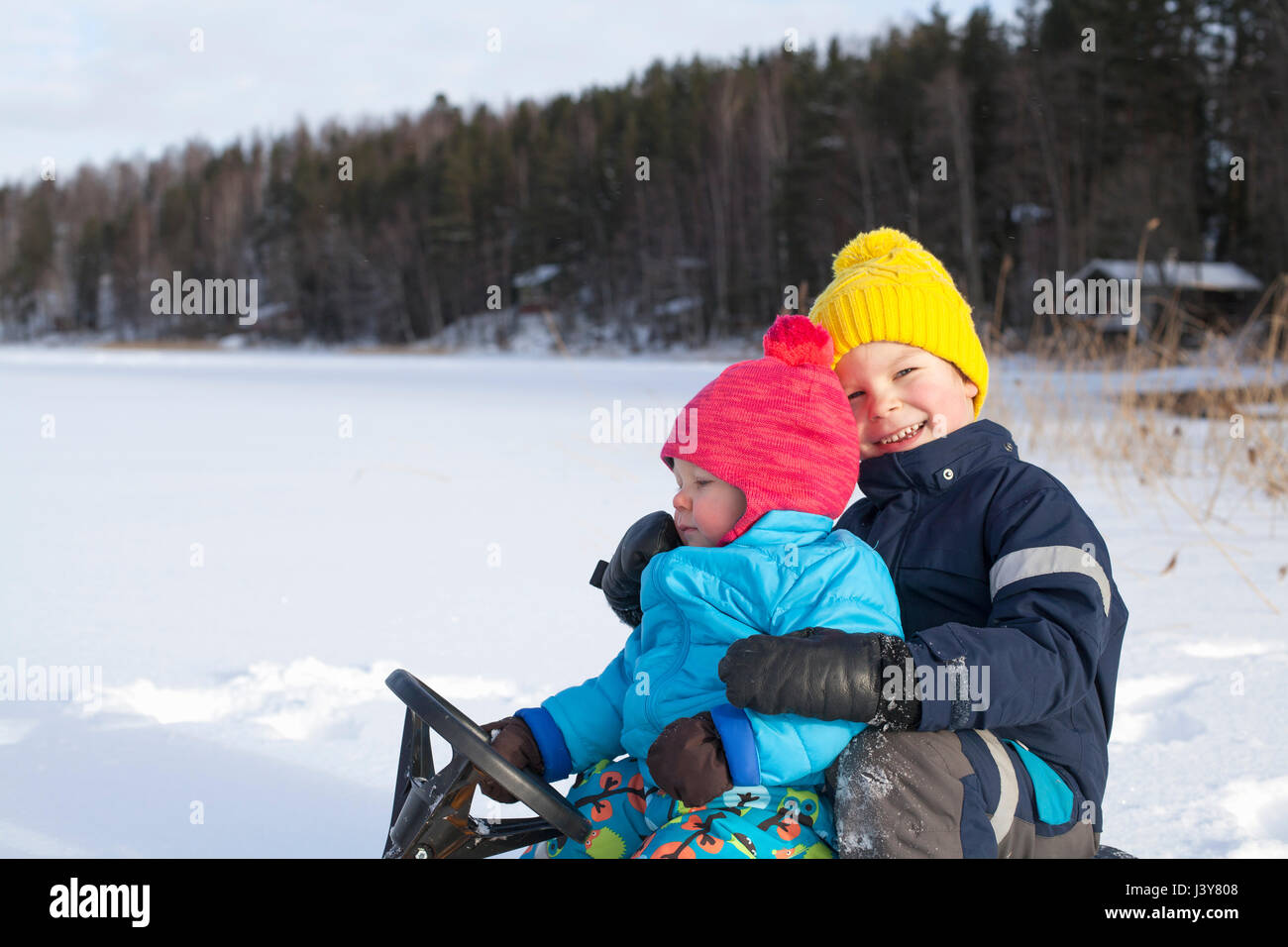 Two young brothers sitting on sledge, in snow covered landscape Stock ...