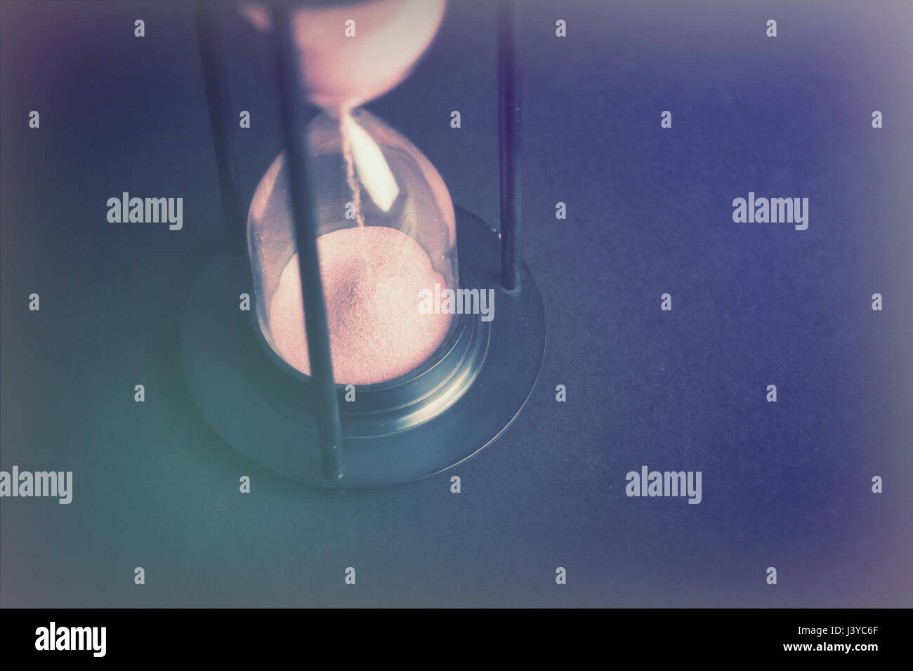 Large hourglass with pink sand against a black background Stock Photo ...