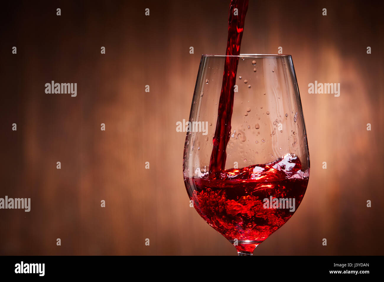 Close-up of tasty red wine pouring in the pure fragile wineglass ...