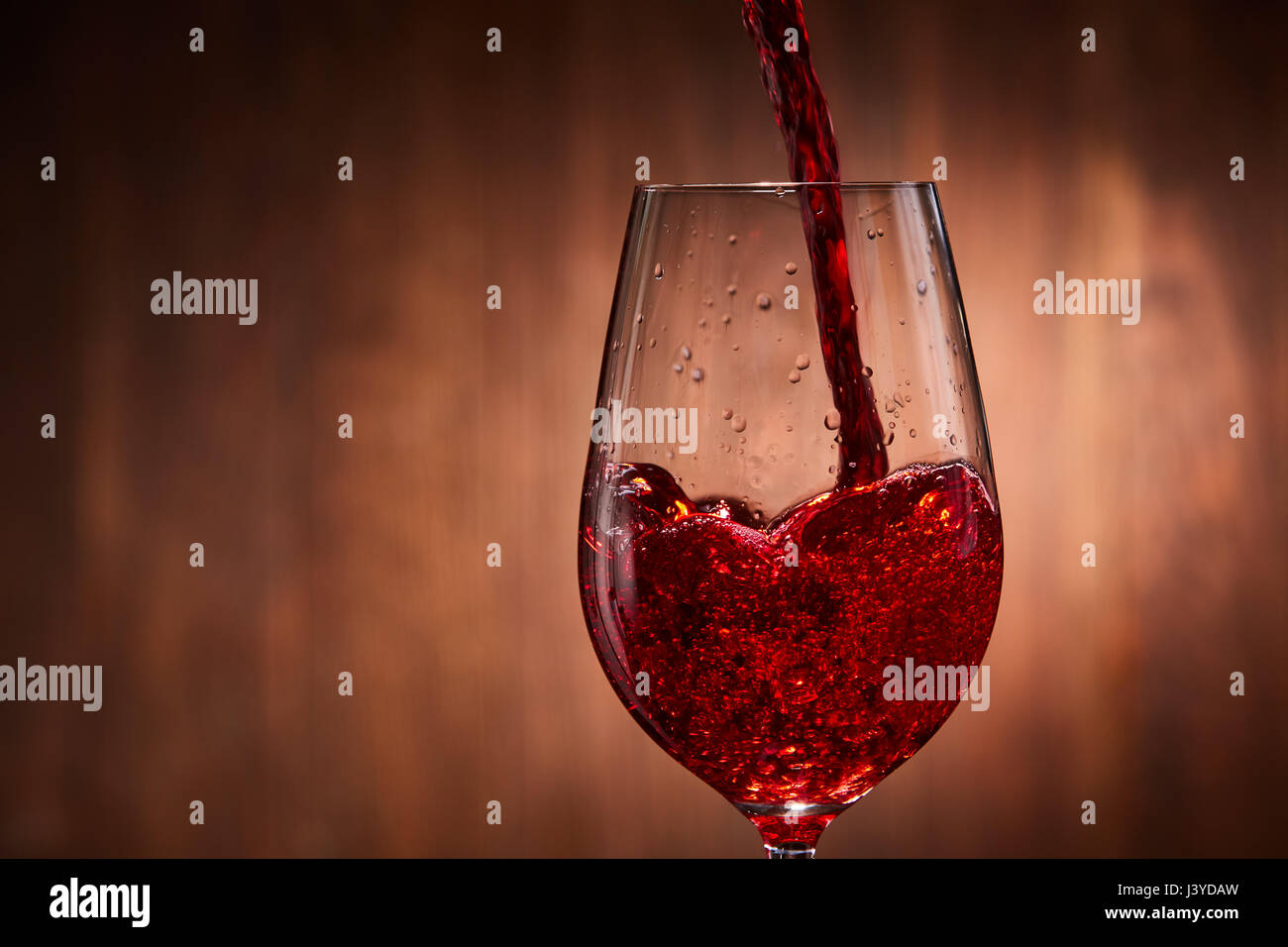 Close-up of tasty red wine pouring in the pure fragile wineglass ...