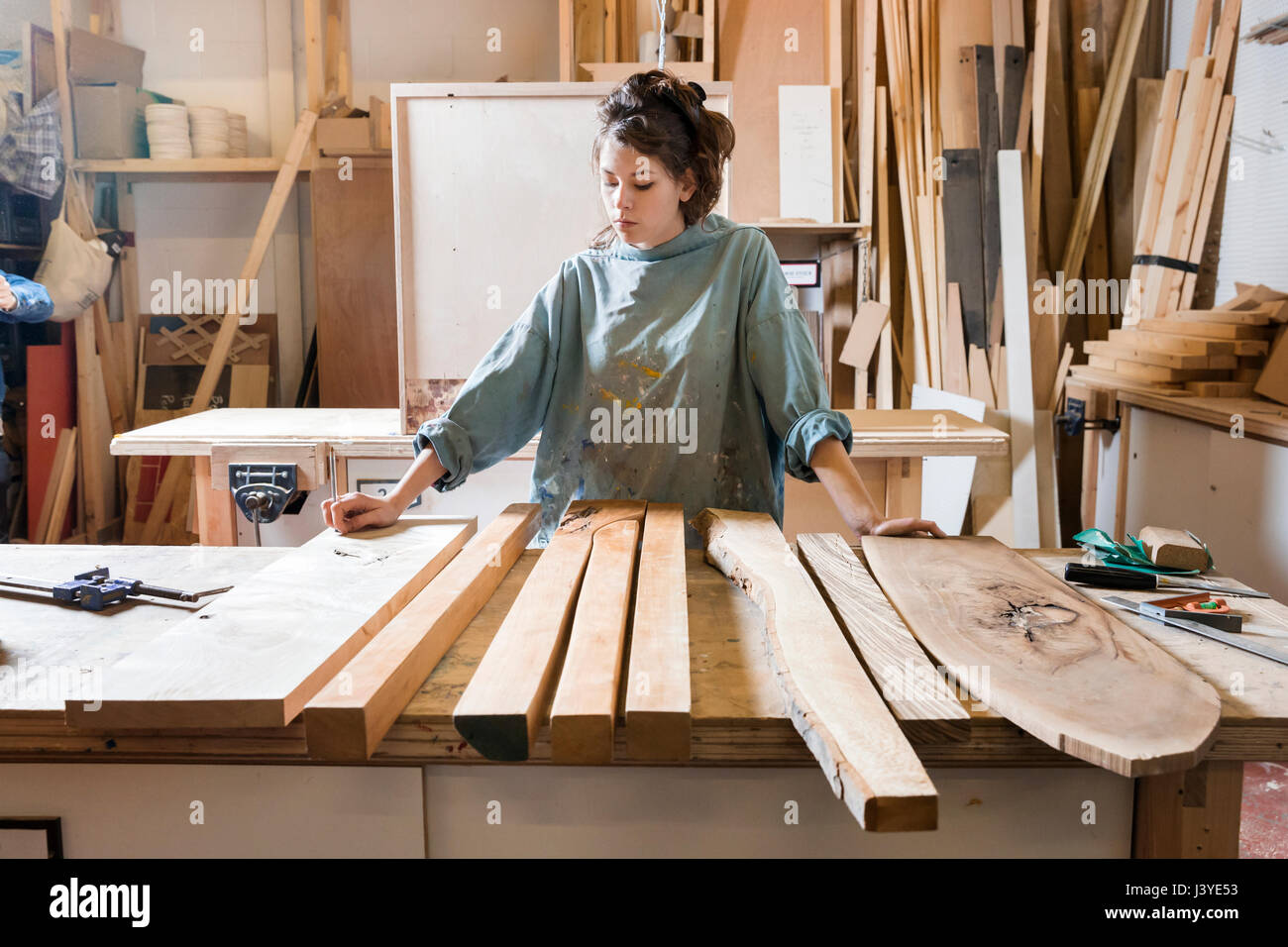 Young woman choosing wood from a selection in a workshop Stock Photo ...
