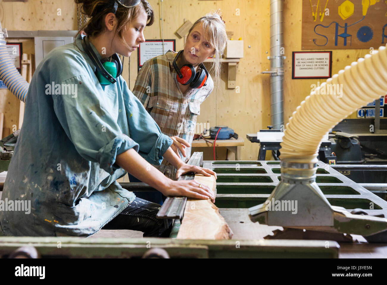 Two women talking and using machinery in a wood workshop Stock Photo ...