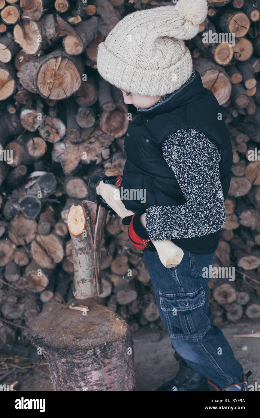 One little boy chopping firewood in the front yard at the day time. Kid ...