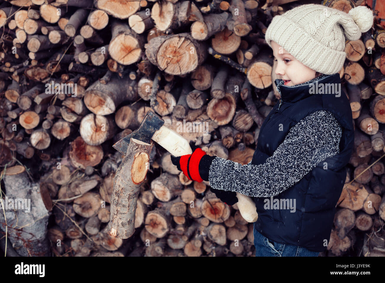 One little boy chopping firewood in the front yard at the day time. Kid ...
