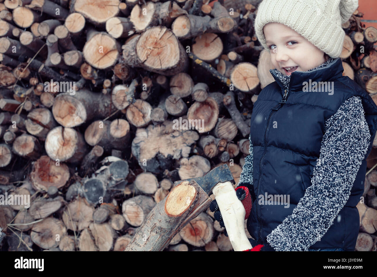 One little boy chopping firewood in the front yard at the day time. Kid ...