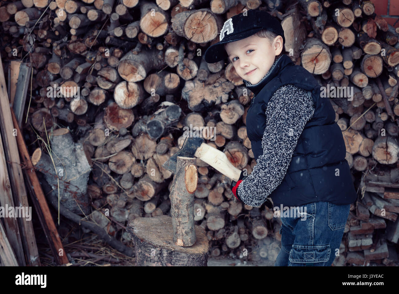 One little boy chopping firewood in the front yard at the day time. Kid ...
