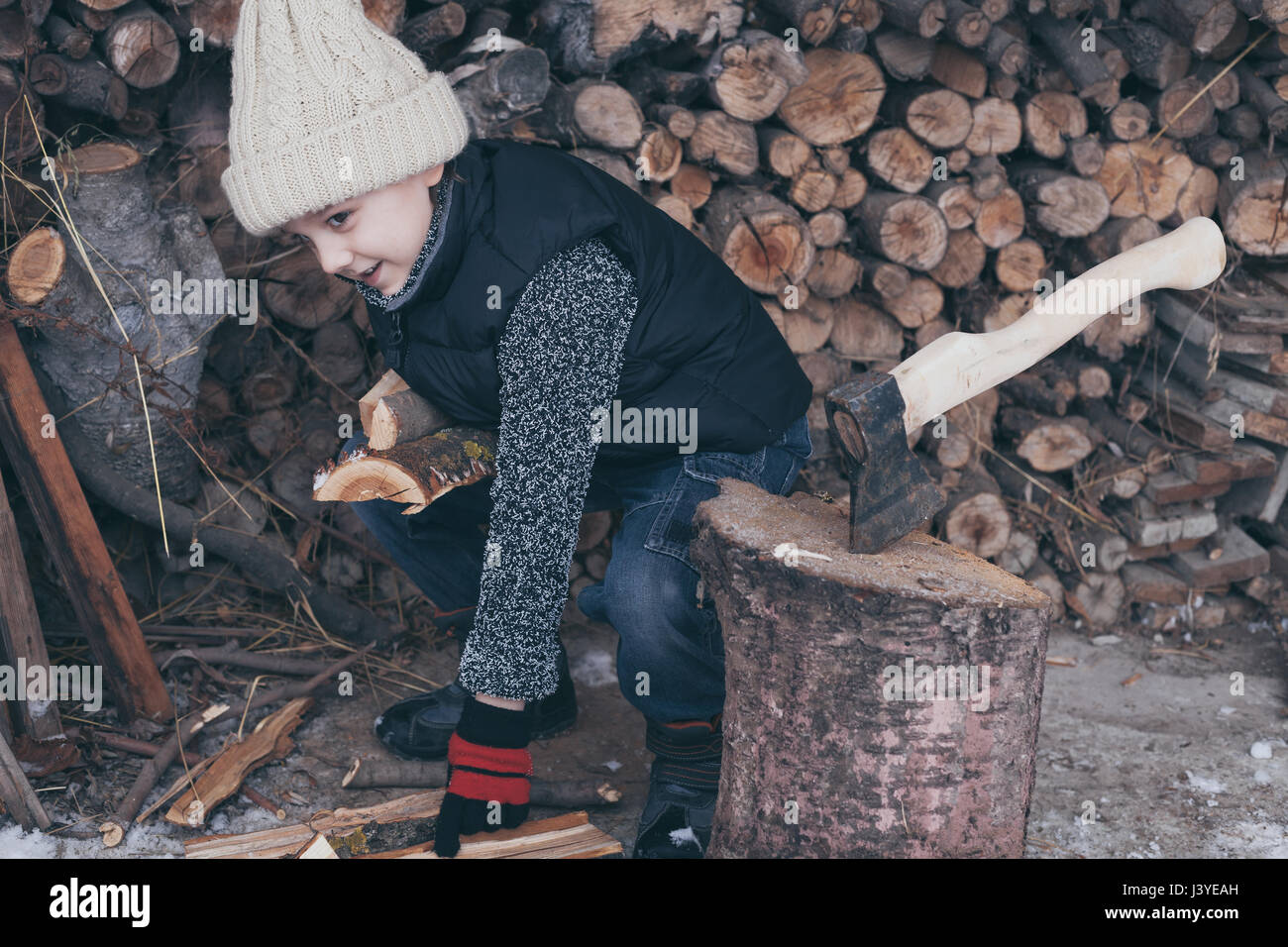 One little boy chopping firewood in the front yard at the day time. Kid ...