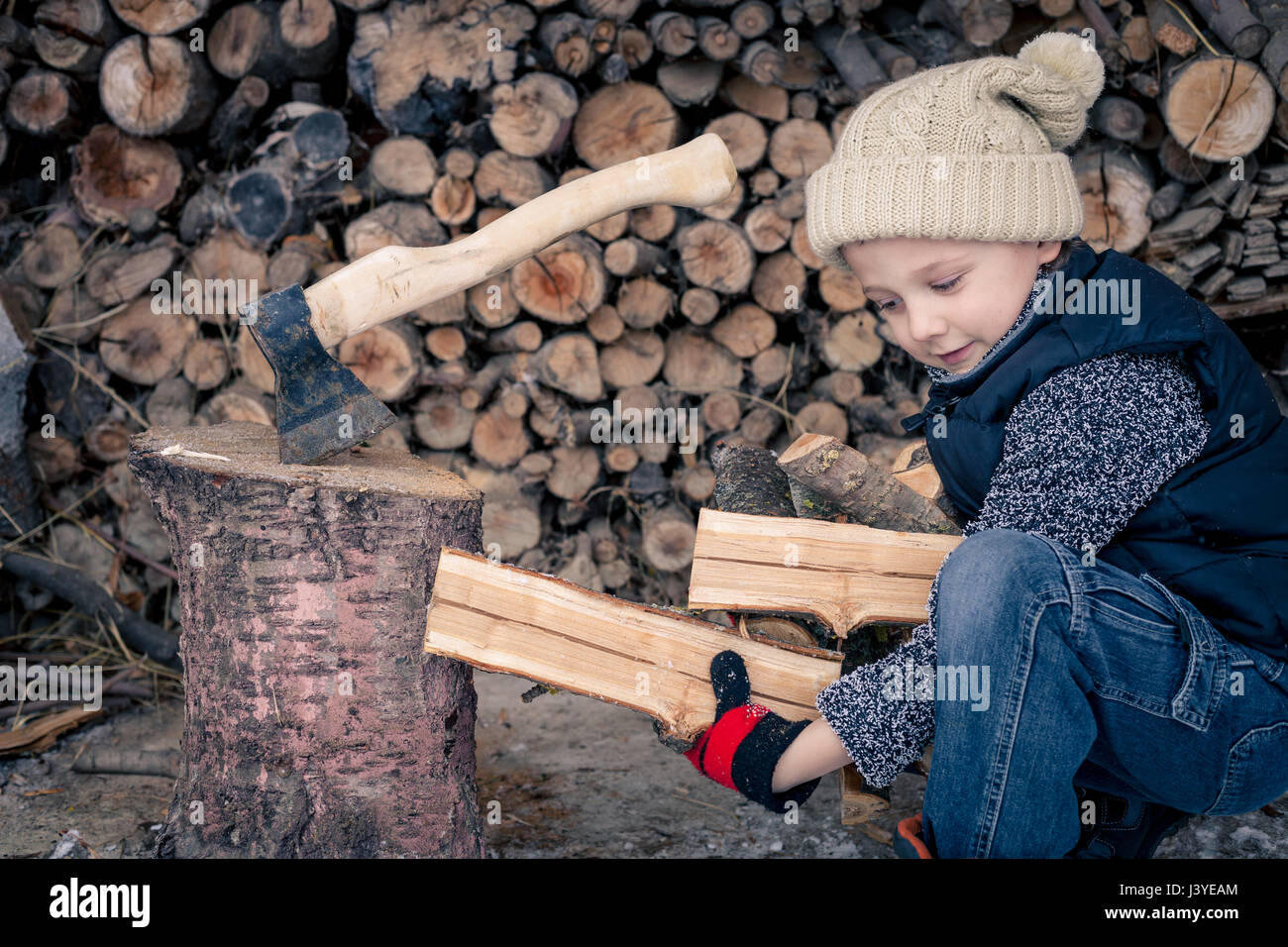 One little boy chopping firewood in the front yard at the day time. Kid ...