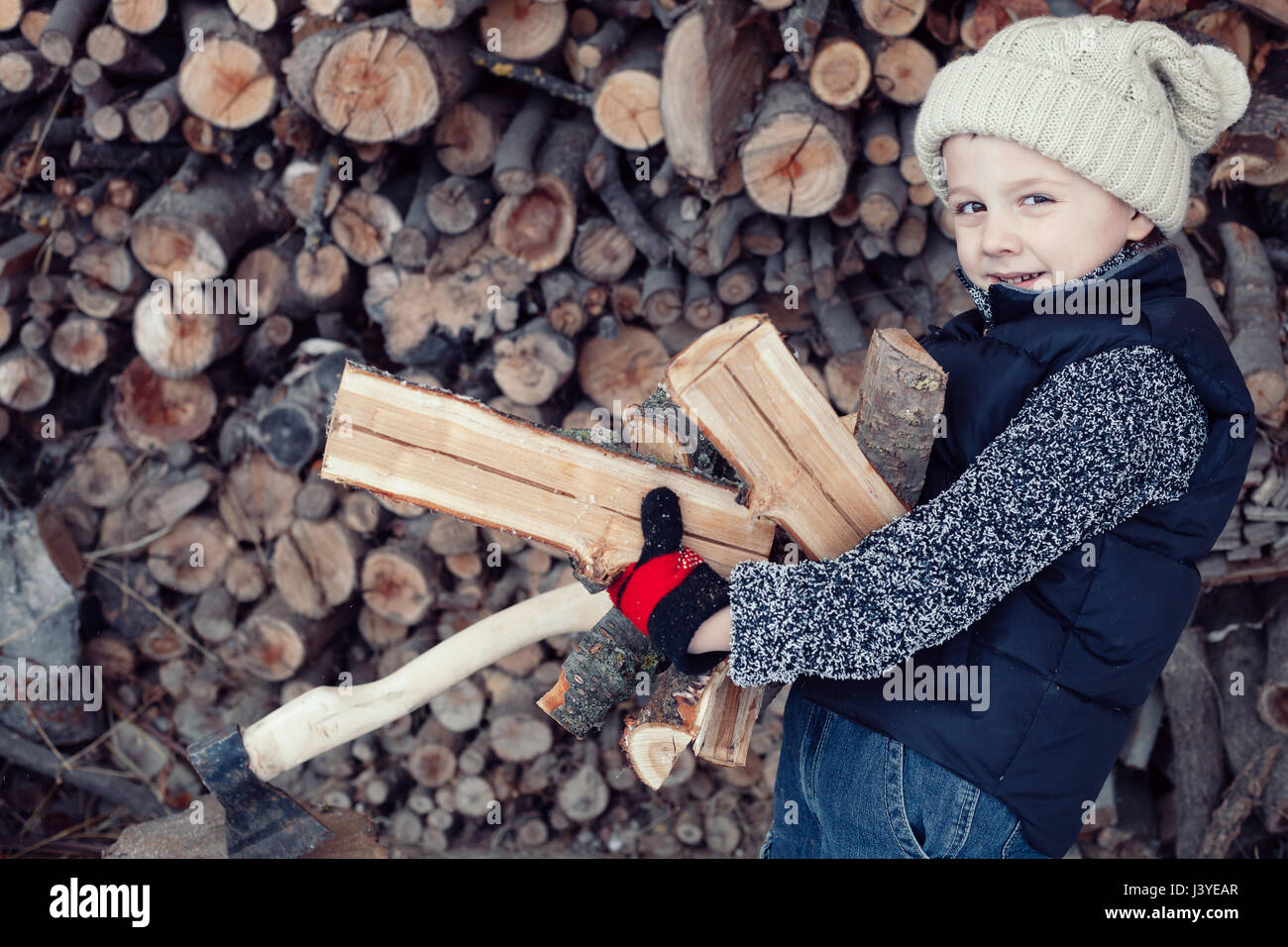 One little boy chopping firewood in the front yard at the day time. Kid ...