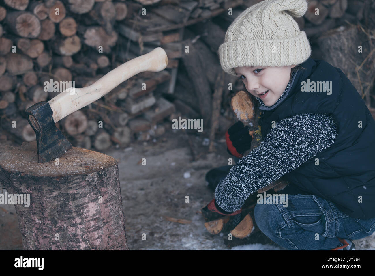 One little boy chopping firewood in the front yard at the day time. Kid ...