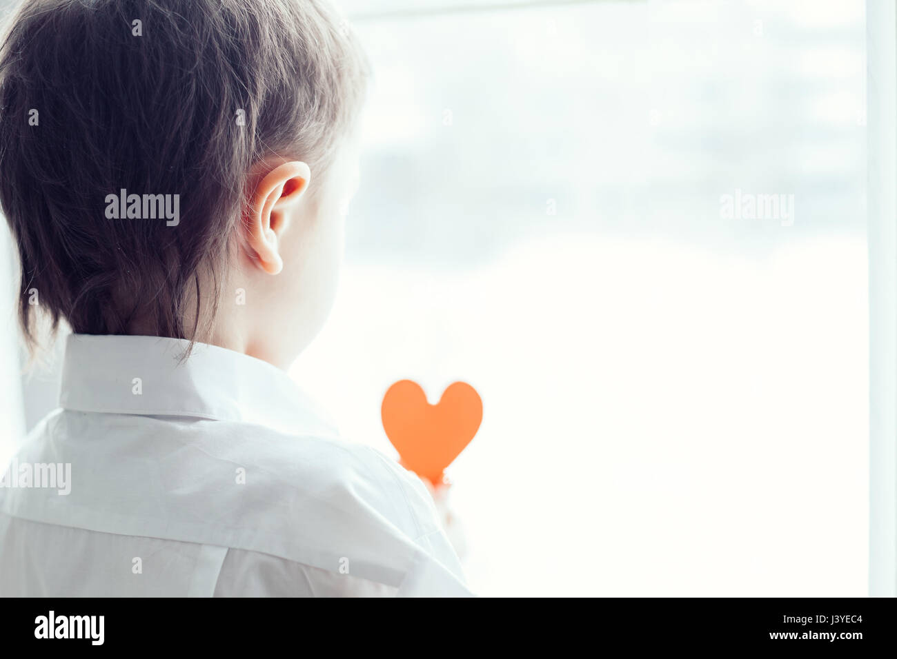 one sad little boy sitting near the window at the day time. Concept of ...