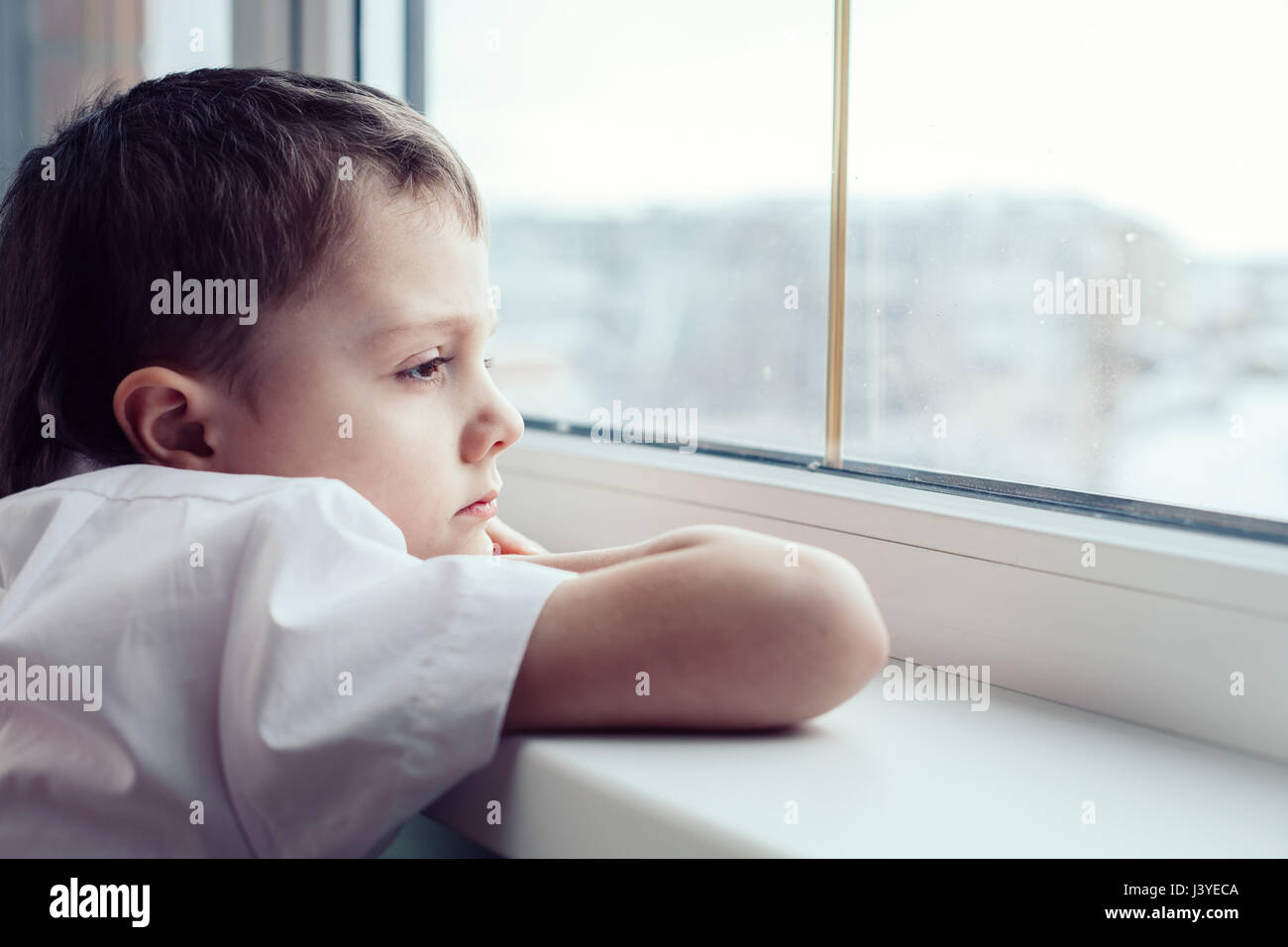one sad little boy sitting near the window at the day time. Concept of ...