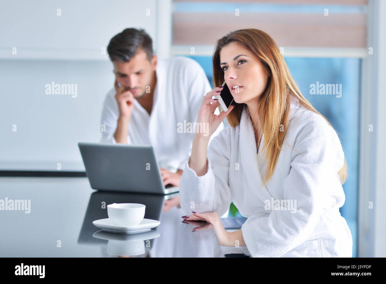 Picture a young woman eating breakfast and taking a phone call, sitting ...