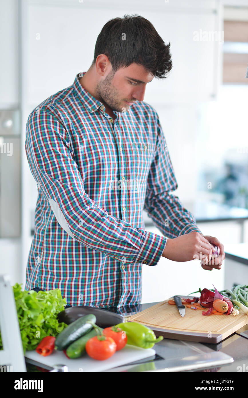 Handsome man cooking at home preparing salad in kitchen Stock Photo - Alamy