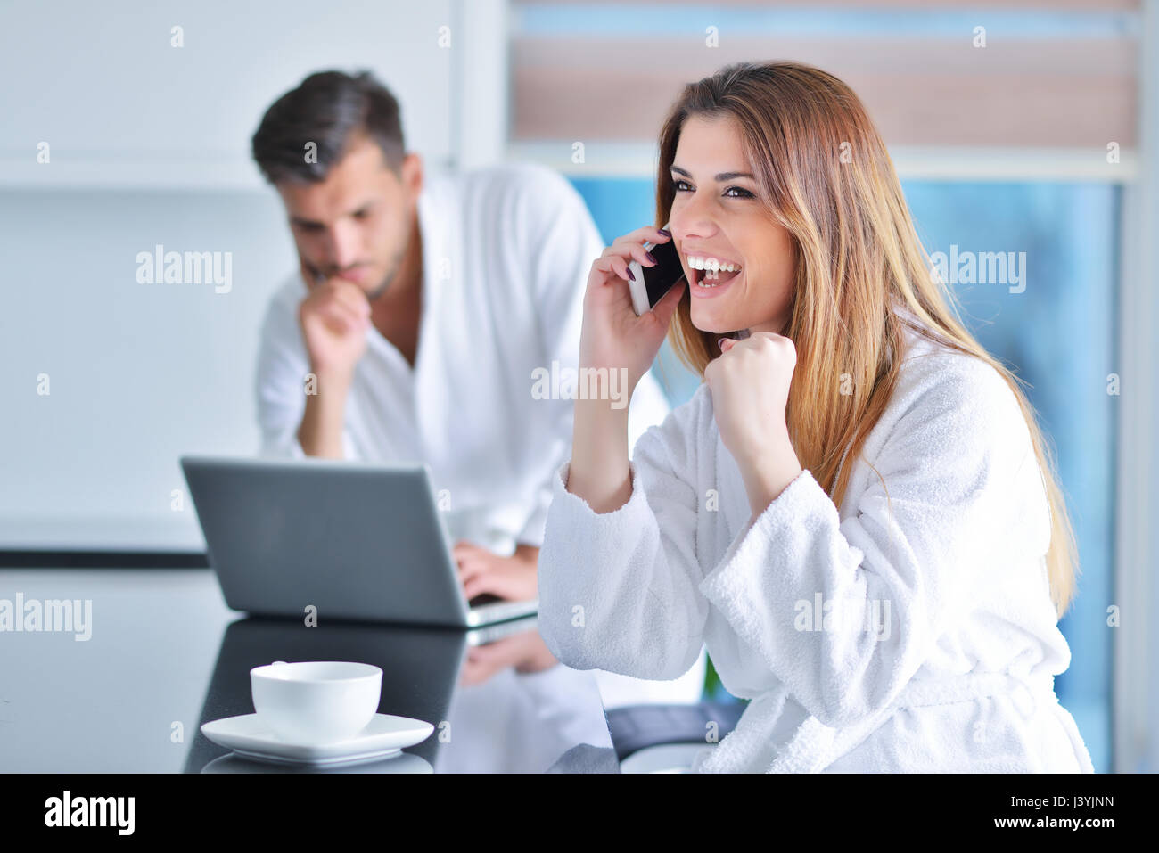 Picture a young woman eating breakfast and taking a phone call, sitting ...