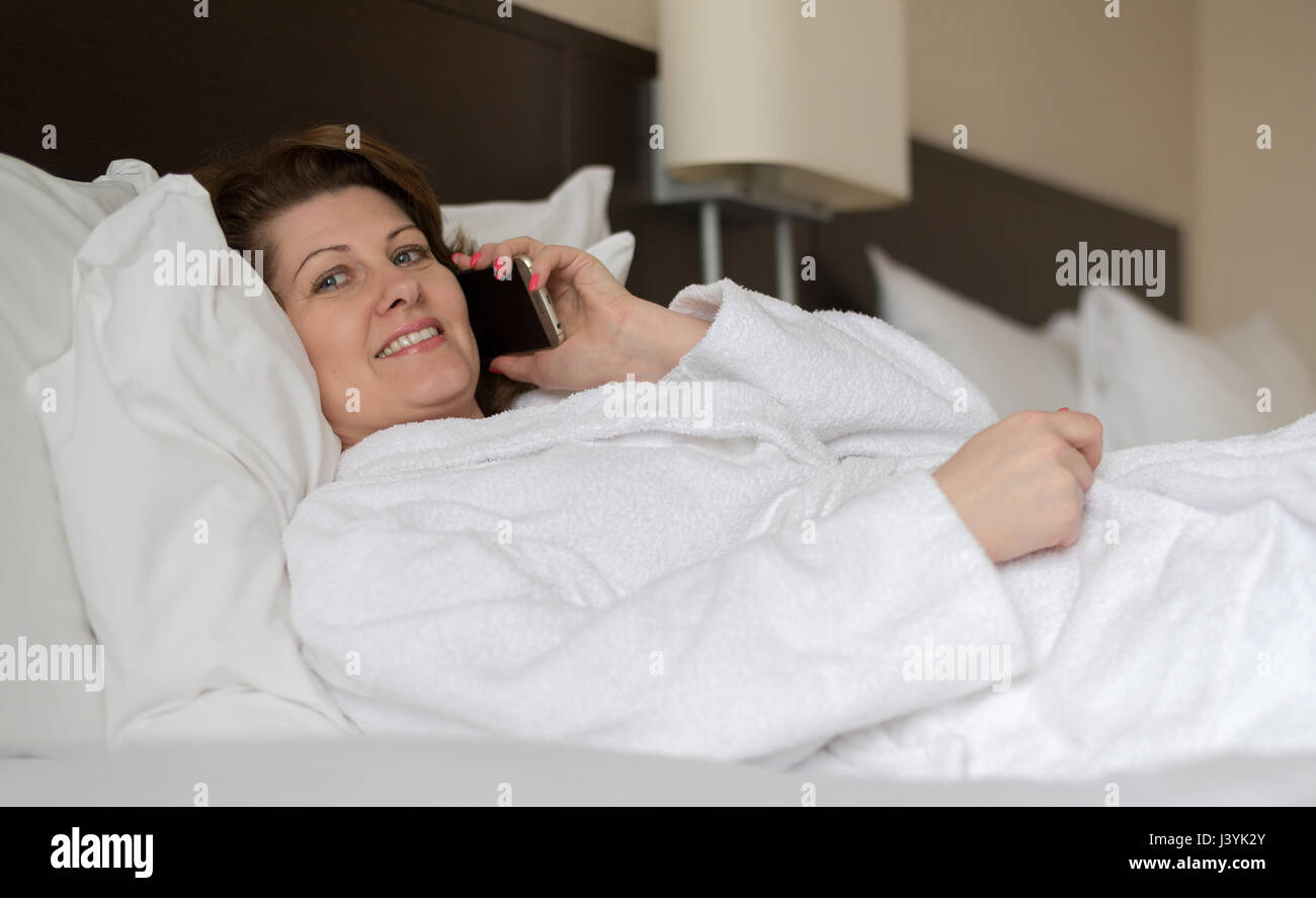 Woman in bathrobe talking on the phone in the hotel room Stock Photo ...