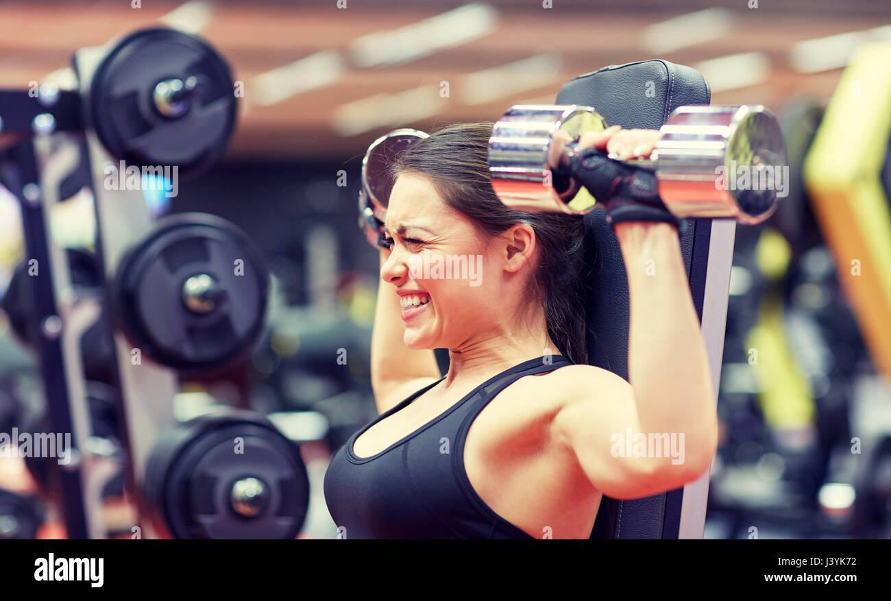 young woman flexing muscles with dumbbell in gym Stock Photo - Alamy