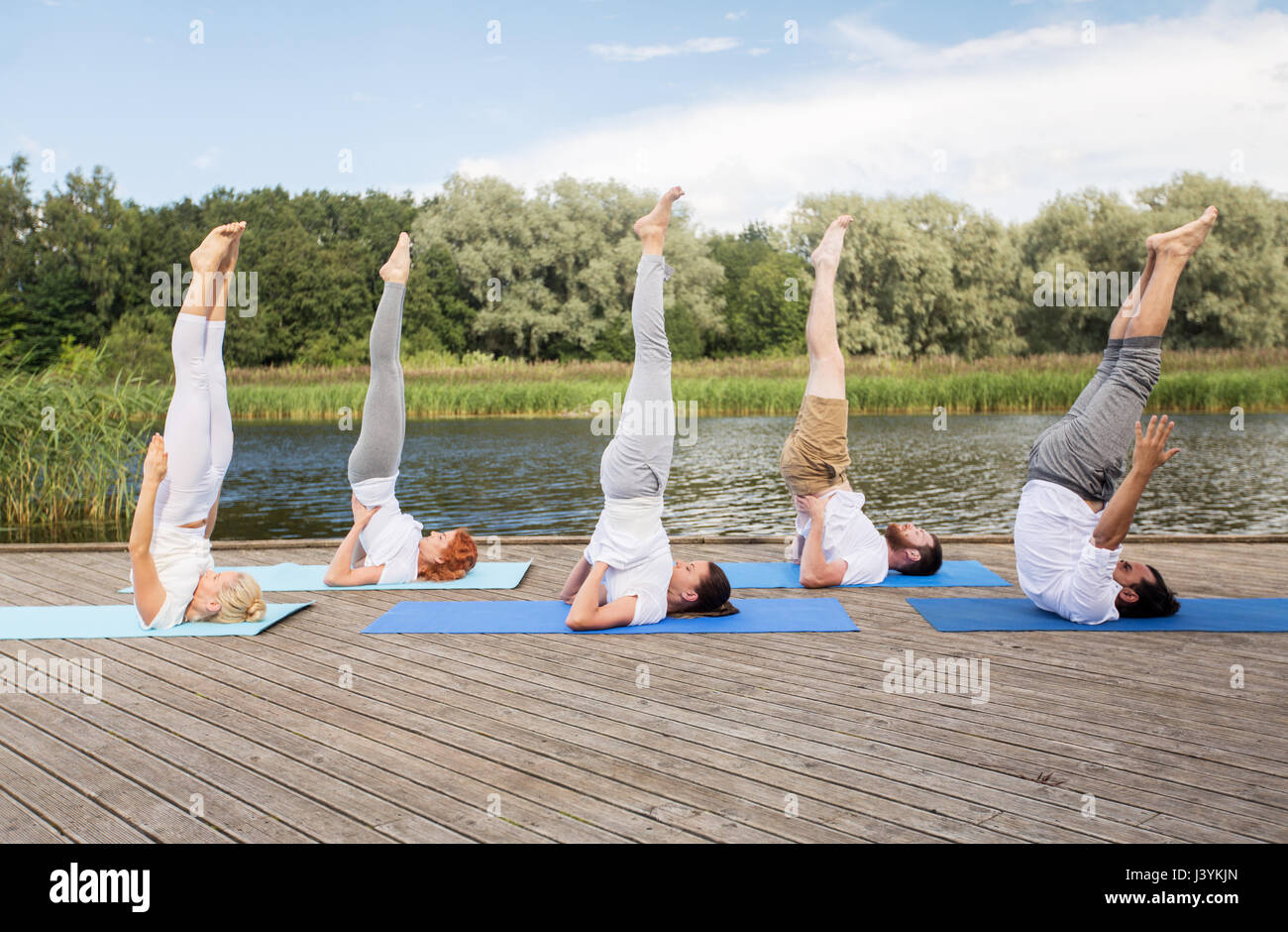 people making yoga in shoulderstand pose on mat Stock Photo - Alamy