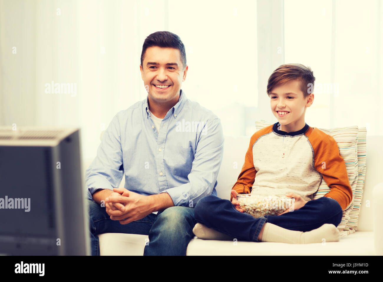 smiling father and son watching tv at home Stock Photo - Alamy