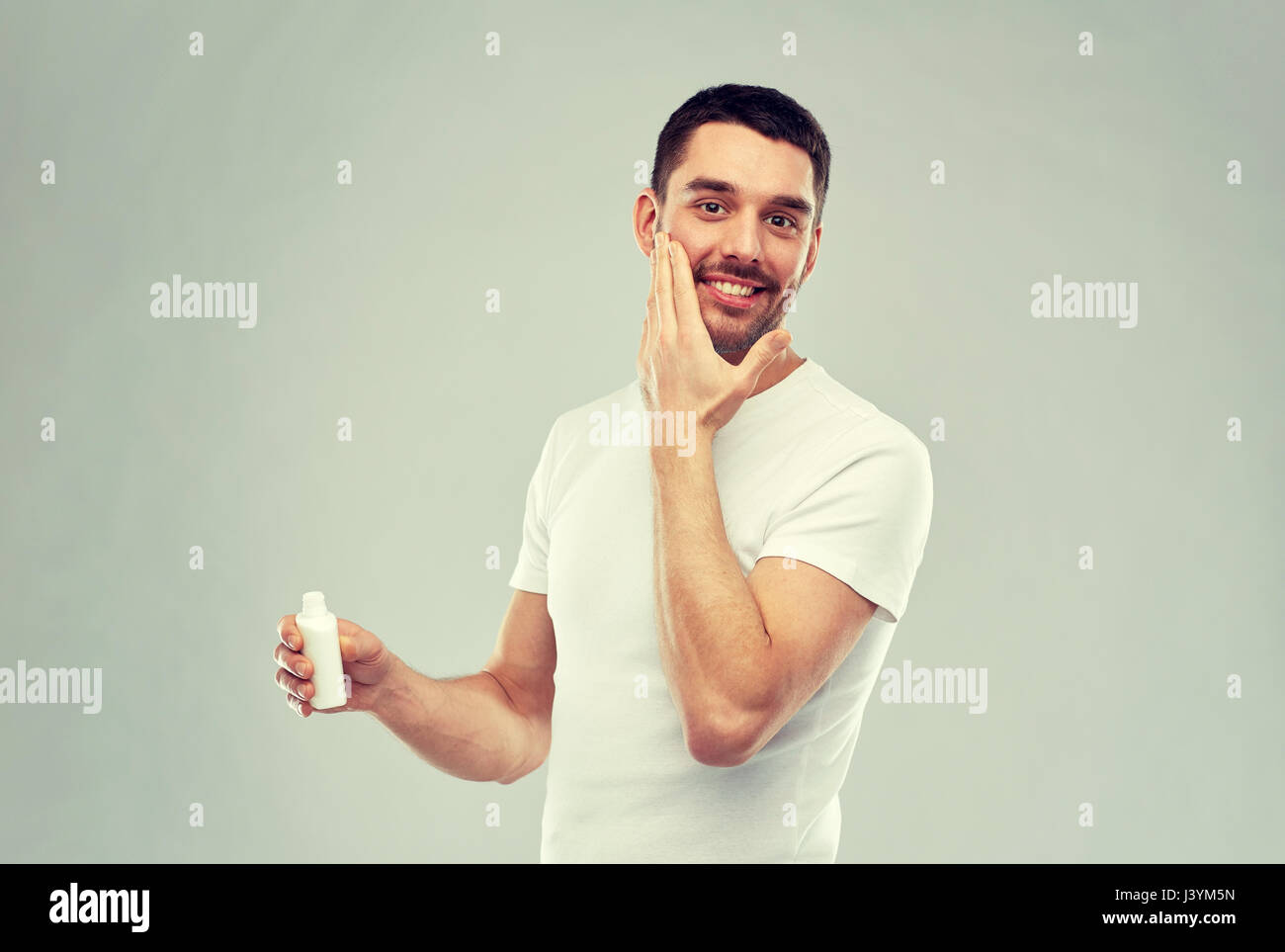 happy young man applying cream or lotion to face Stock Photo - Alamy