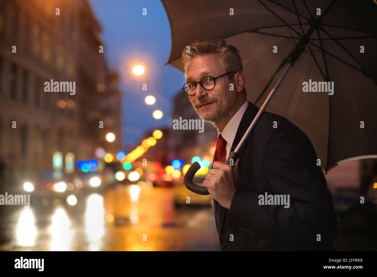 Cheerful man walking in the street under the rain Stock Photo - Alamy