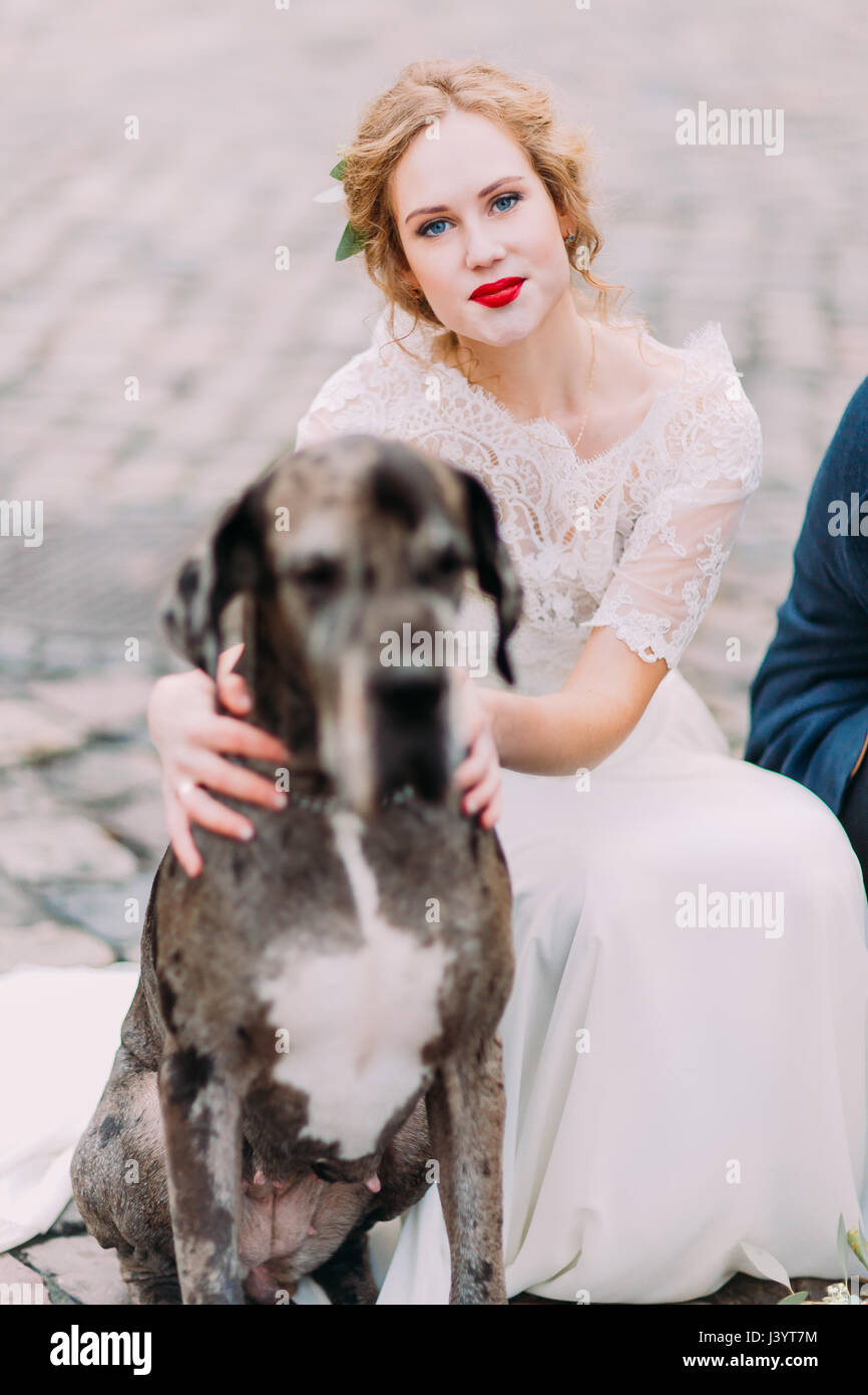 Beautiful blond bride with bright red lips holds her dog close up Stock ...