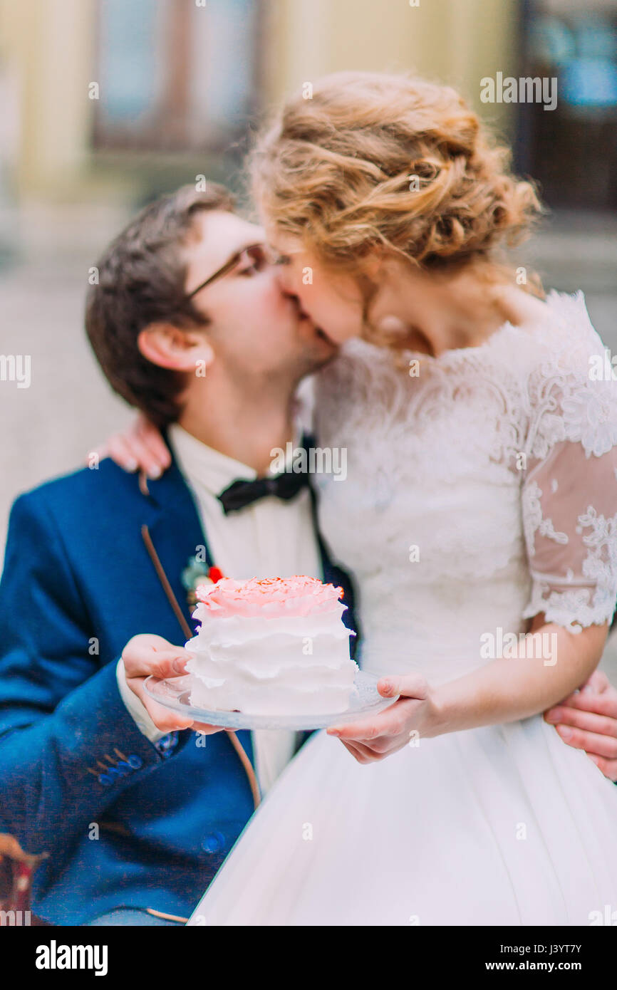 Happy newlyweds softly kissing and holding their wedding cake Stock ...