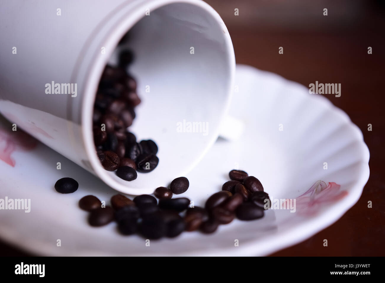 Coffee beans Pouring from coffee cup Stock Photo - Alamy
