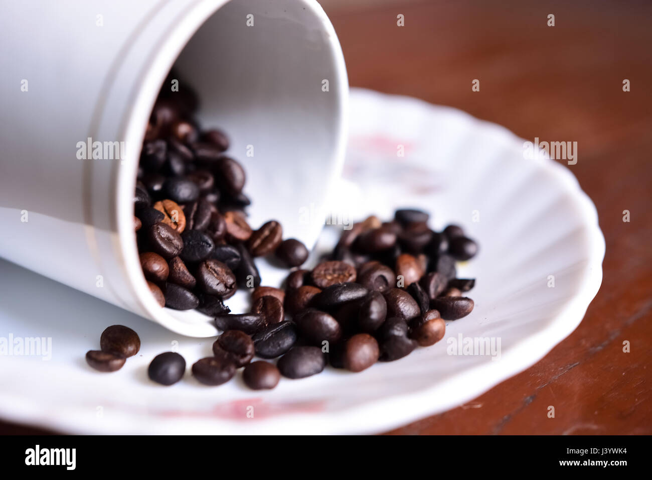 Coffee beans Pouring from coffee cup Stock Photo - Alamy
