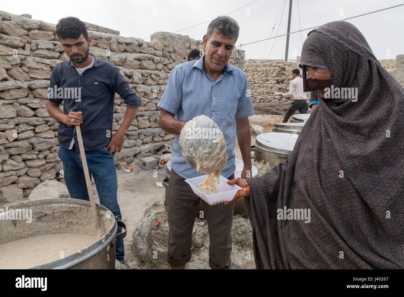 Men Serving Halim -local porridge- to a lady in a plastic container ...