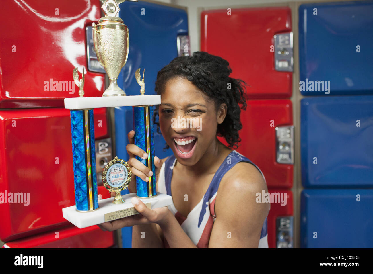 A young woman with a trophy in fornt of red and blue lockers Stock ...