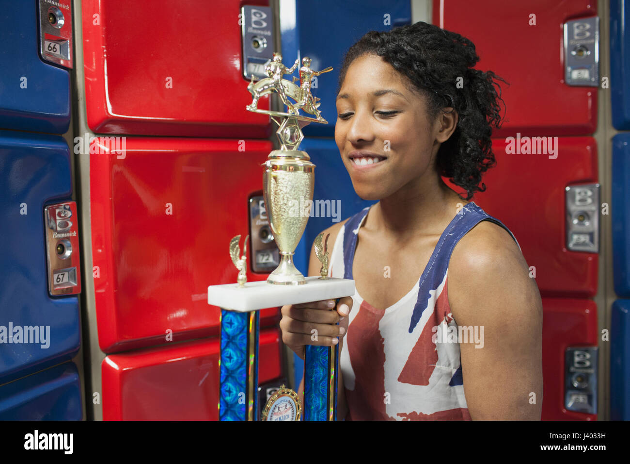 A young woman with a trophy in fornt of red and blue lockers Stock ...