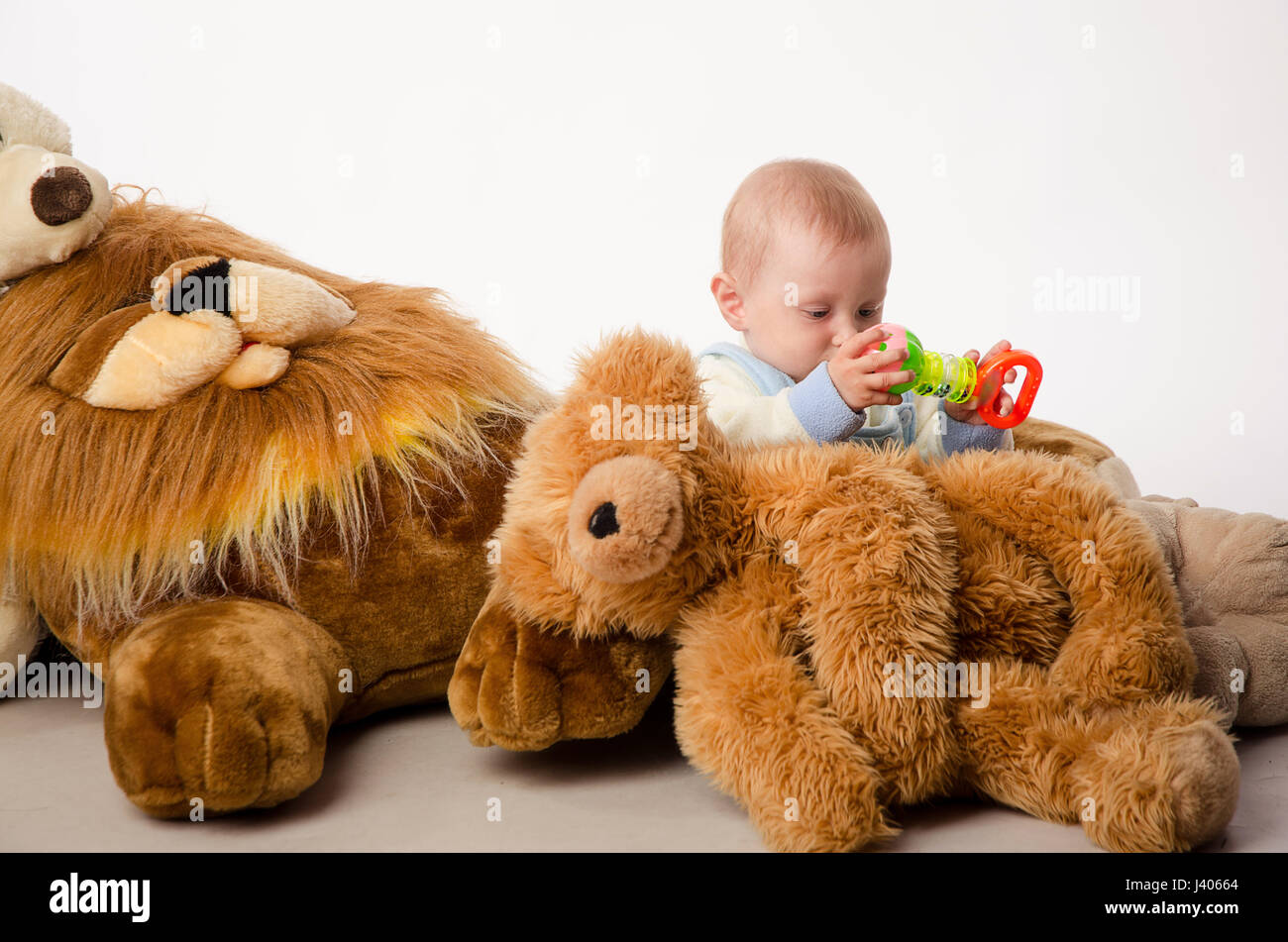 little girl sits among many plush toys Stock Photo - Alamy
