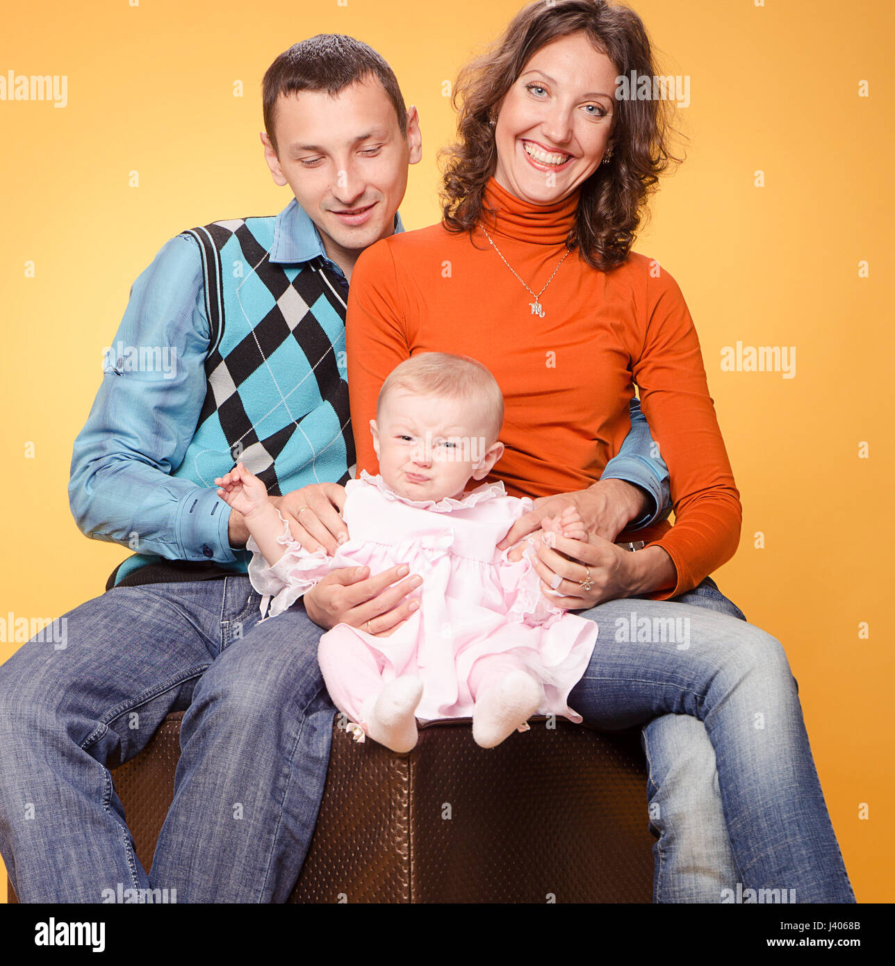 Parents and daughter, on an orange background Stock Photo - Alamy