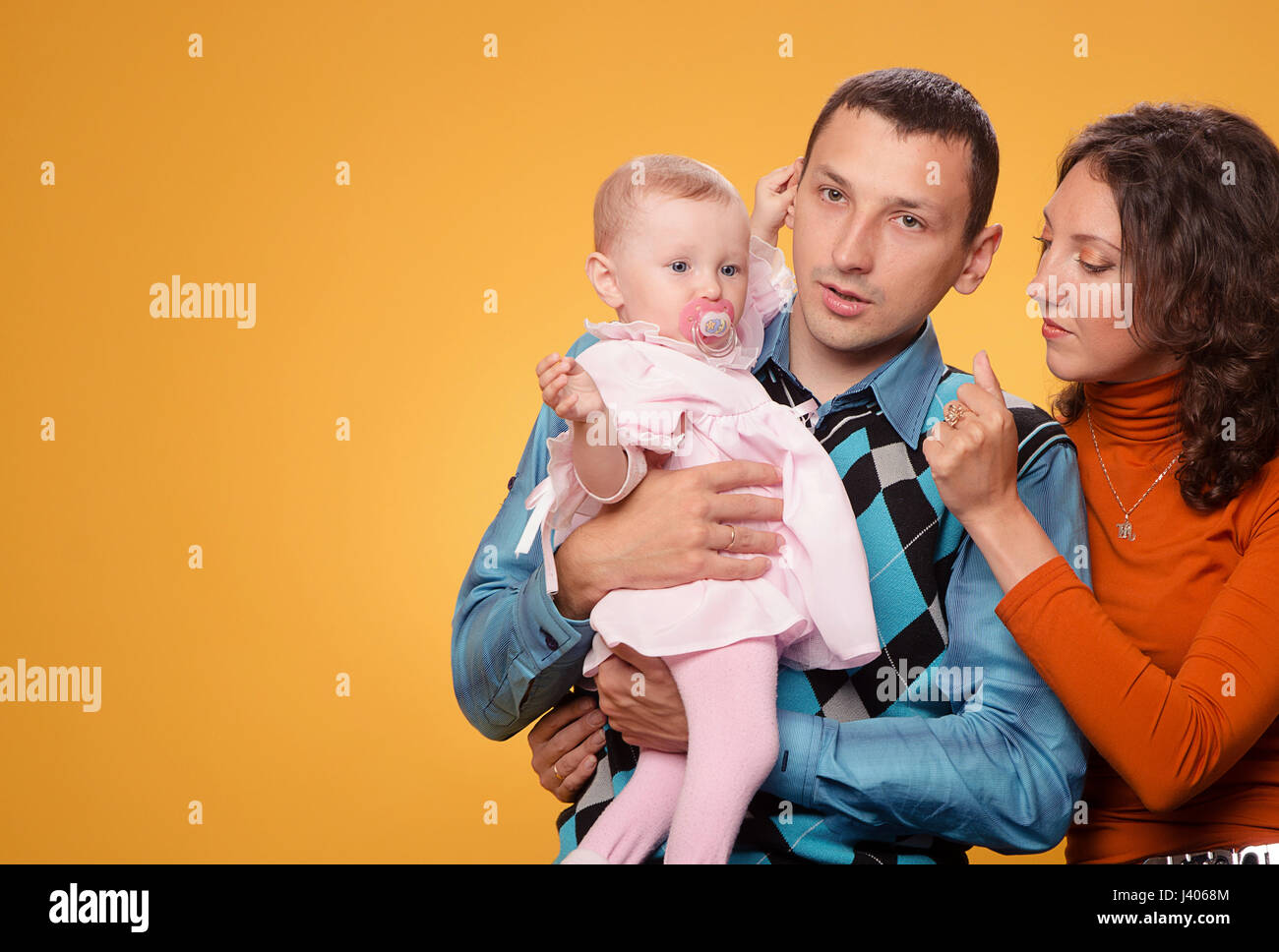 Parents and daughter, on an orange background Stock Photo - Alamy