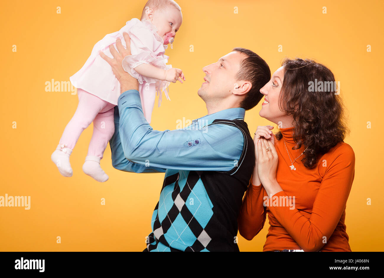 Parents and daughter, on an orange background Stock Photo - Alamy