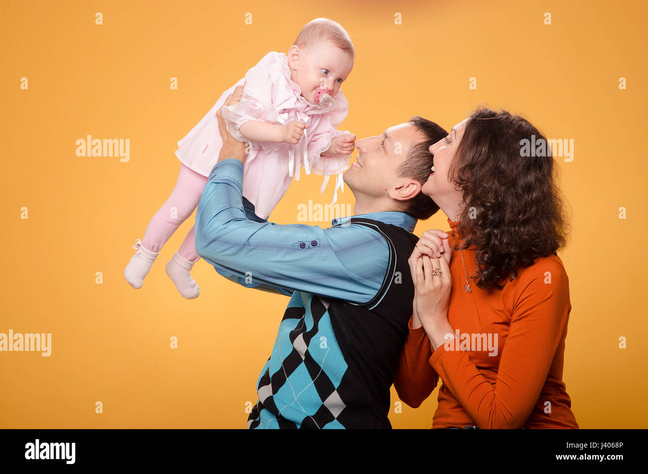 Parents and daughter, on an orange background Stock Photo - Alamy