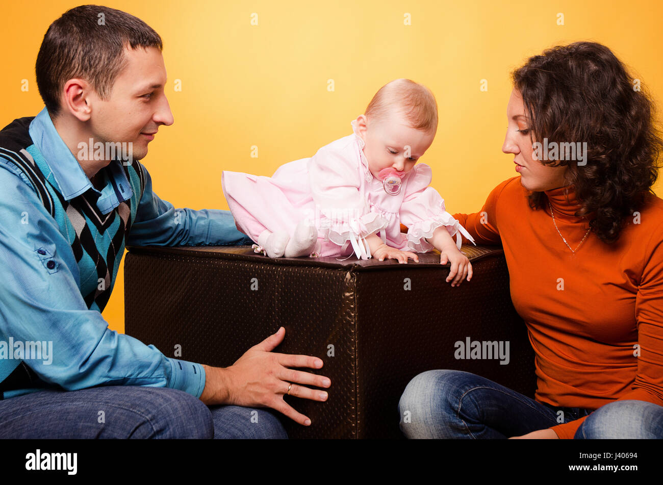 Parents and daughter, on an orange background Stock Photo - Alamy