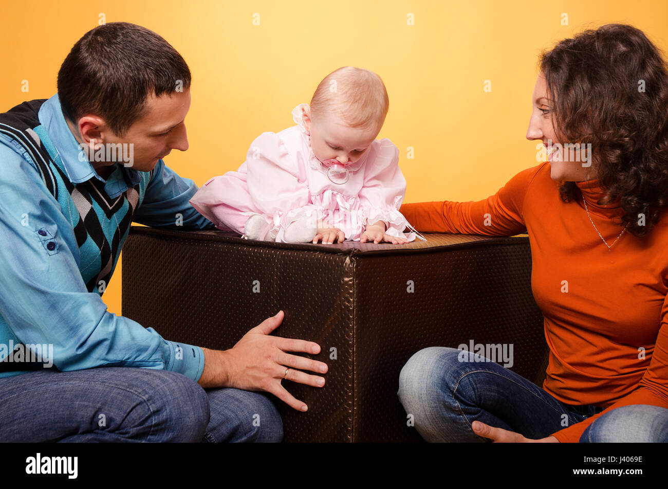 Parents and daughter, on an orange background Stock Photo - Alamy