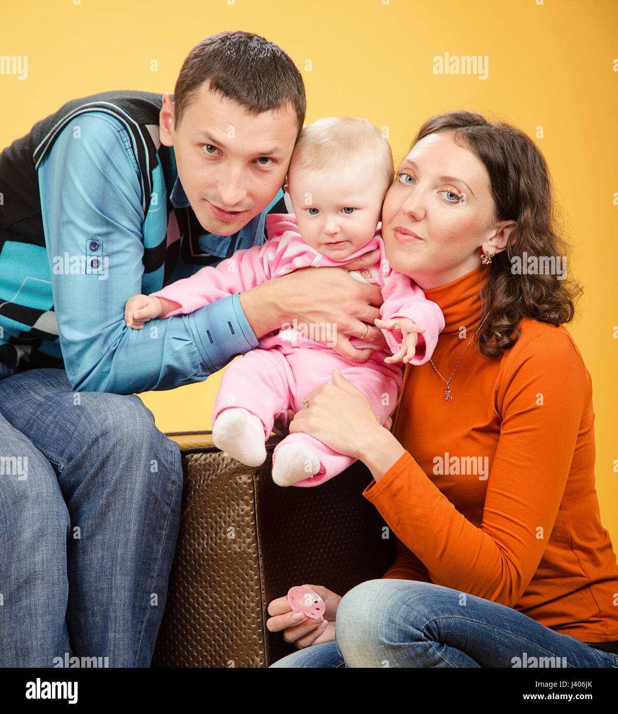Parents and daughter, on an orange background Stock Photo - Alamy