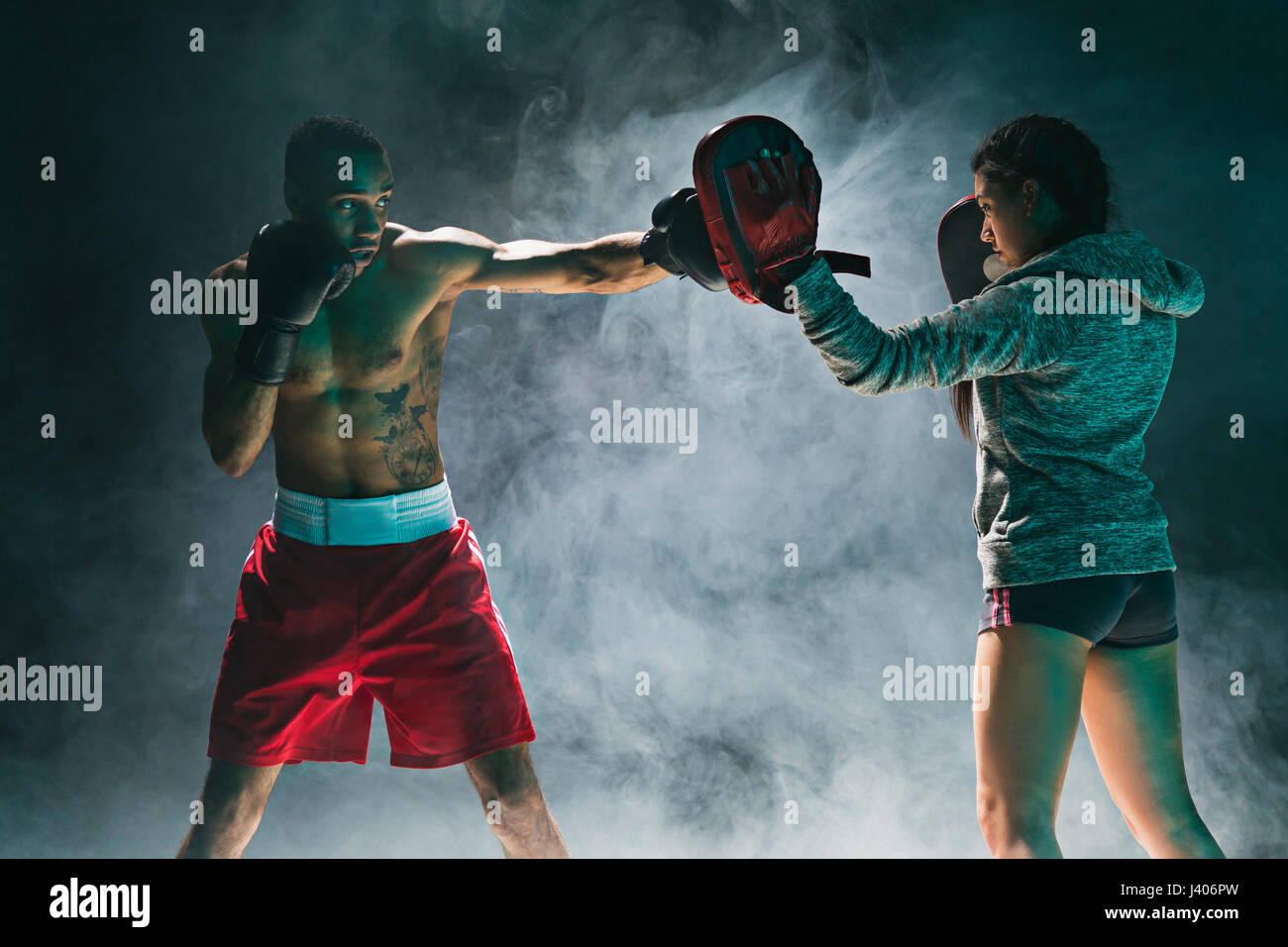 Handsome Afro American boxer with bare torso is practicing punches with ...